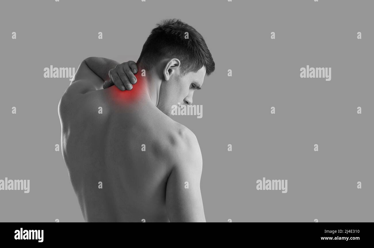 Serious young man is holding his neck in pain due to muscle spasm or ...