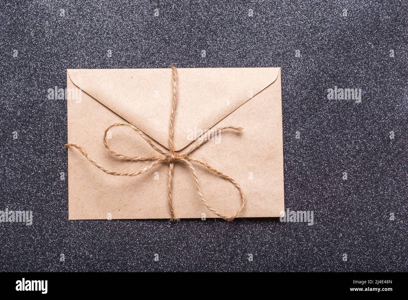 Closed brown craft envelope tied with twine with a bow on a black ...