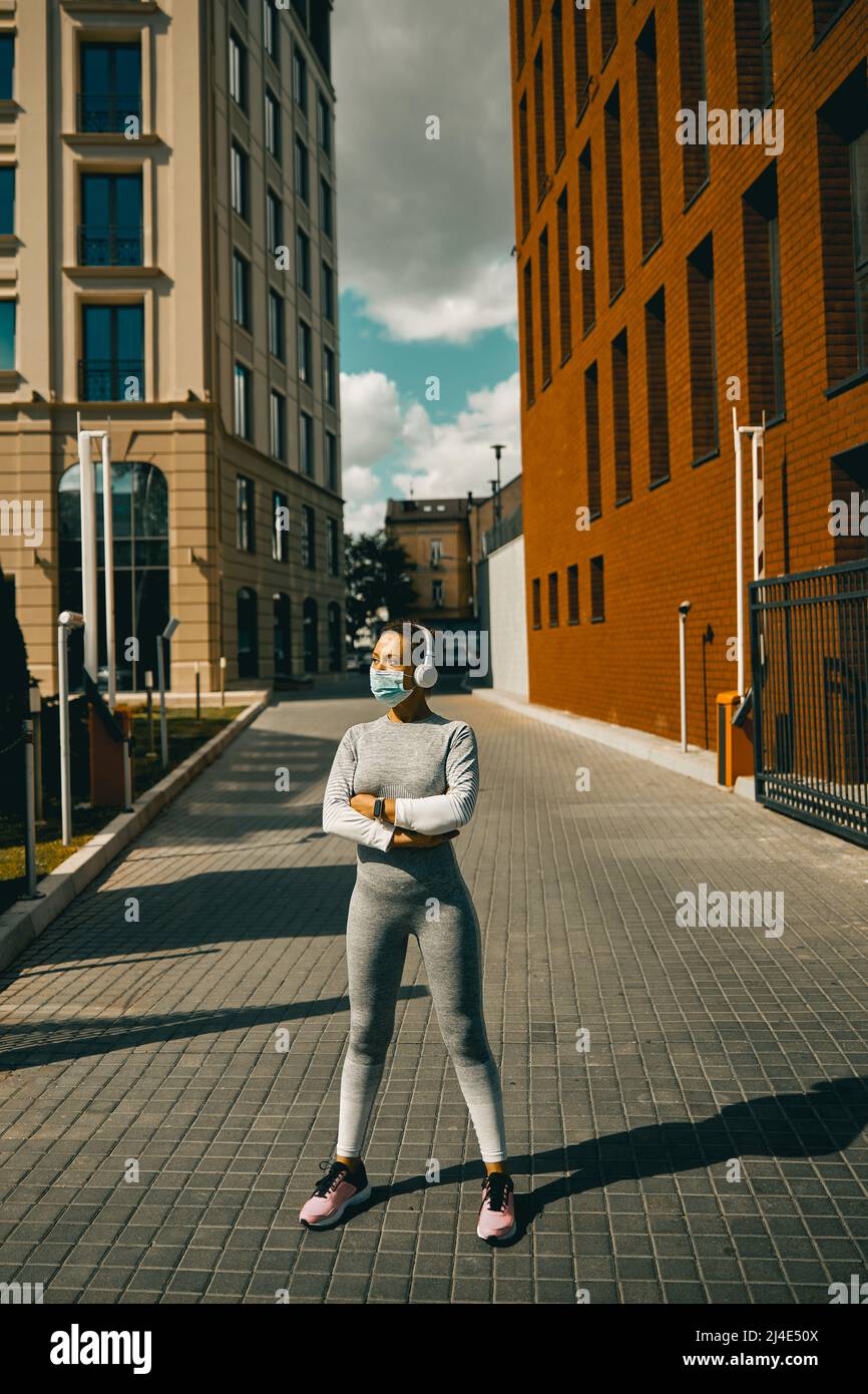 Sporty female runner standing on an urban street alone during Covid19 ...