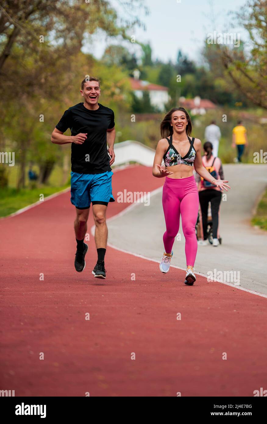 Attractive young couple in sporty outfits running together and having ...