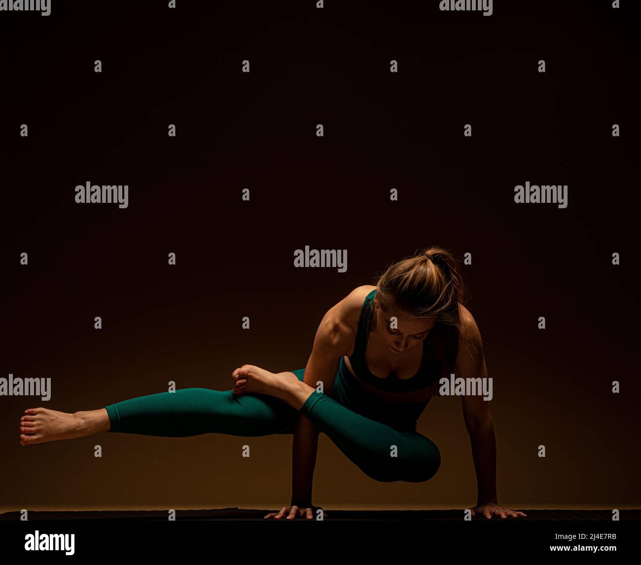 Attractive and beautiful young girl is doing the bakasana pose with her ...