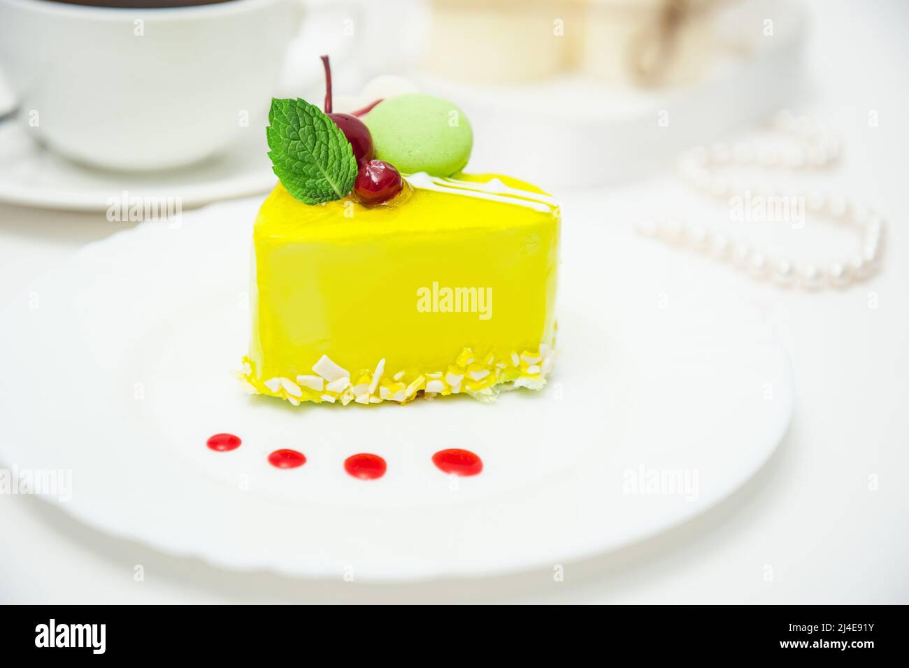 lemon yellow heart cake with cherries and cream on white background ...