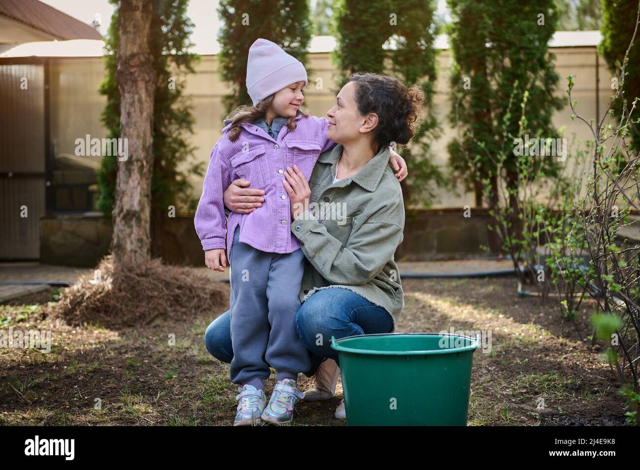 Happy delightful mother and daughter enjoying gardening in the backyard ...
