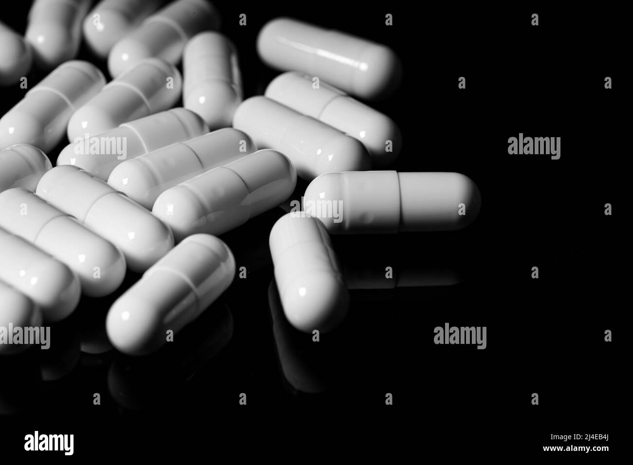 Macro Close up of white painkiller capsule on a reflective black ...