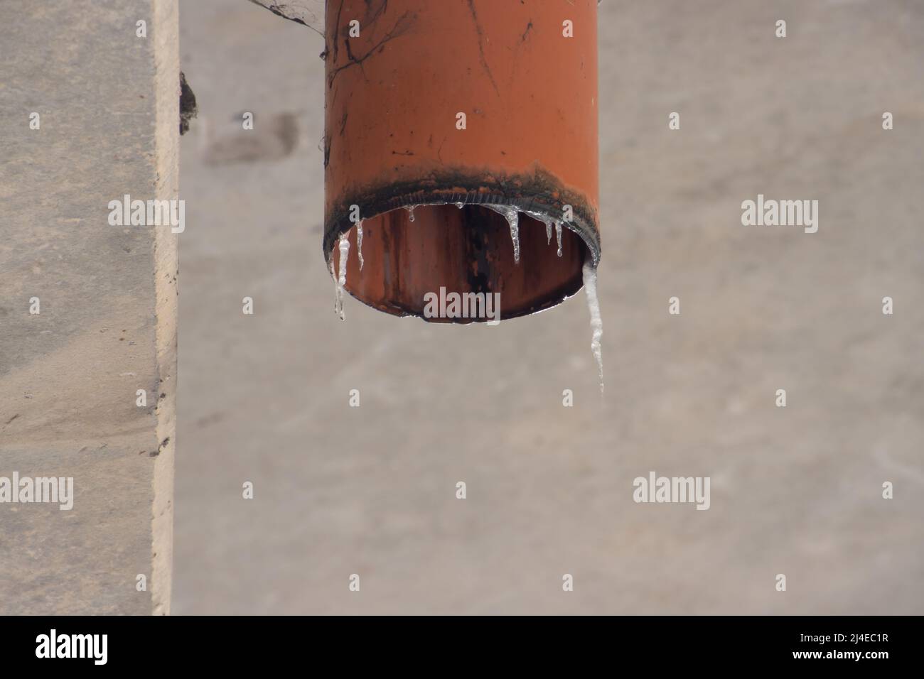 Melting icicles on a red plastic drainage pipe Stock Photo - Alamy