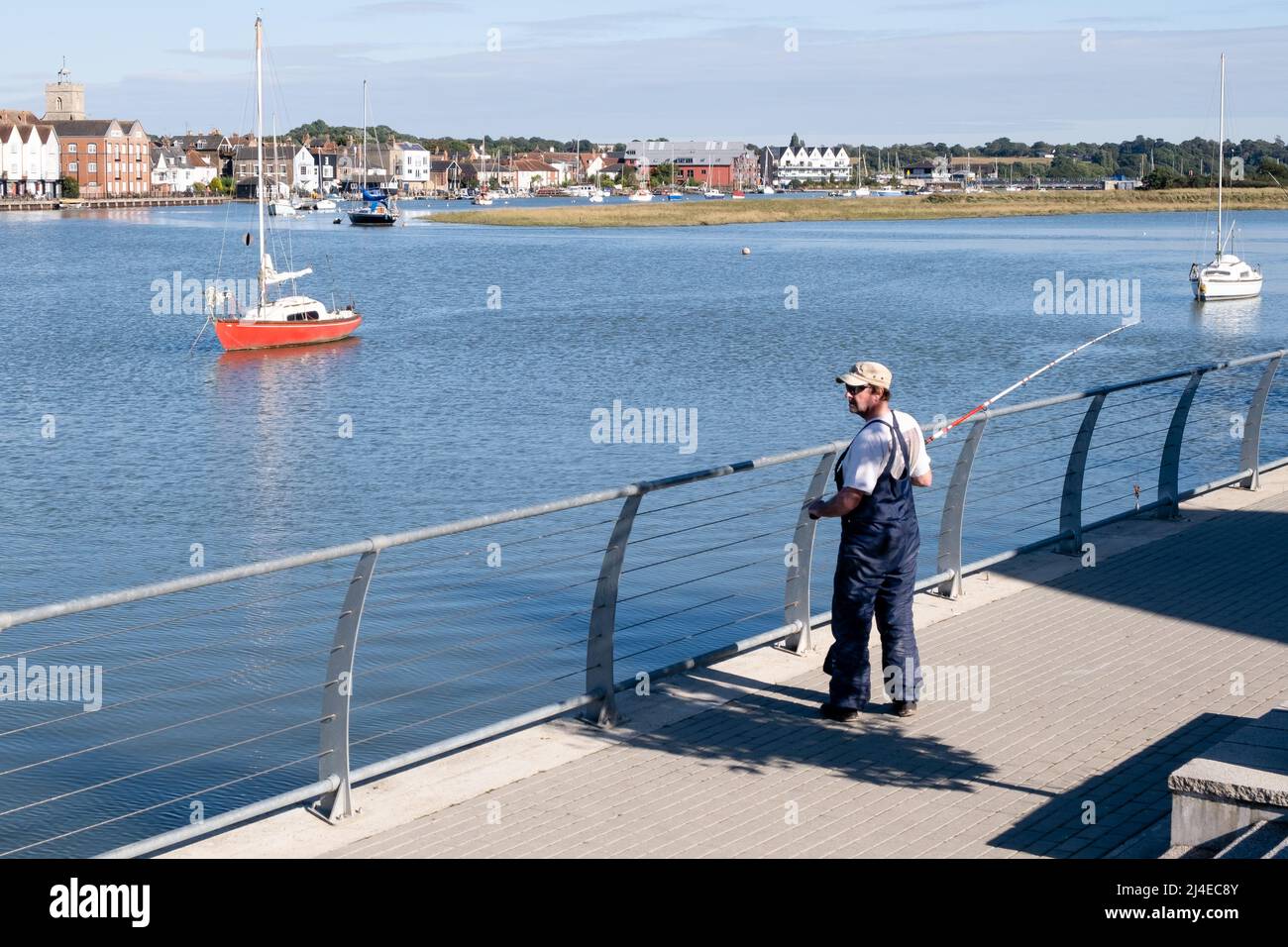 Fisherman holding red and white fishing rod, wearing blue overalls and ...