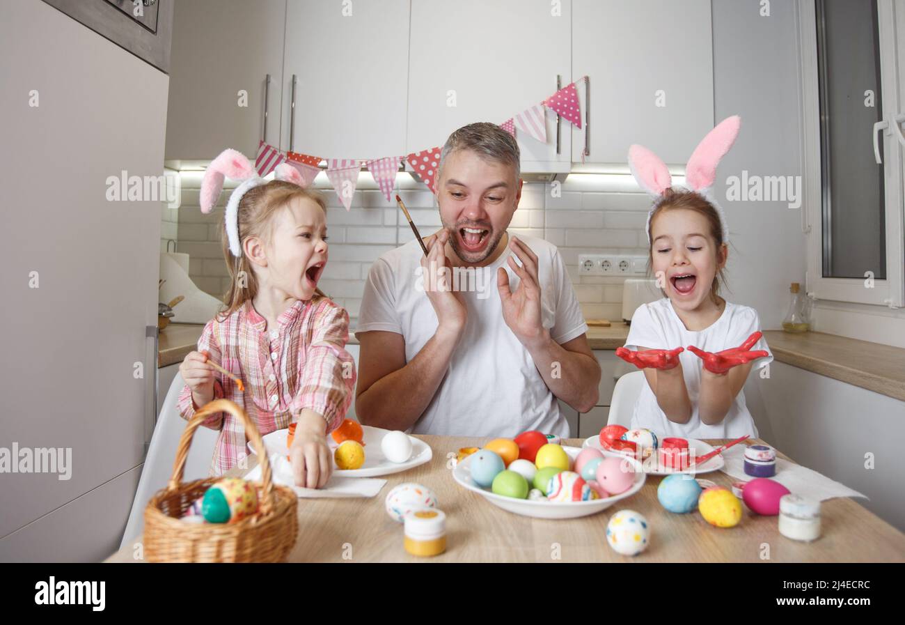 a happy father with two young daughters are laughing and dabbling ...