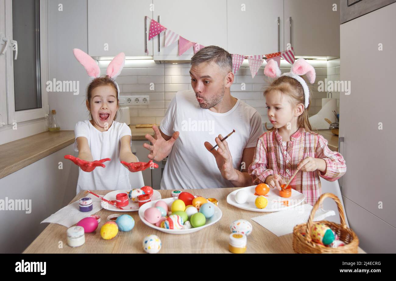 a happy father with two young daughters are laughing and dabbling ...