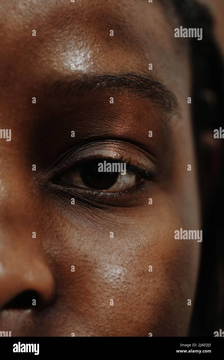 Close-up of African young woman with dark brown eyes looking at camera ...