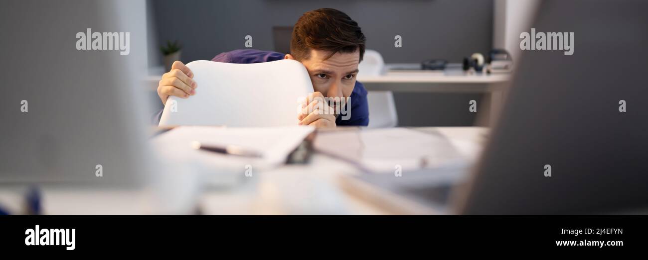 Frightened Businessman Hiding Behind Chair At Workplace Stock Photo - Alamy