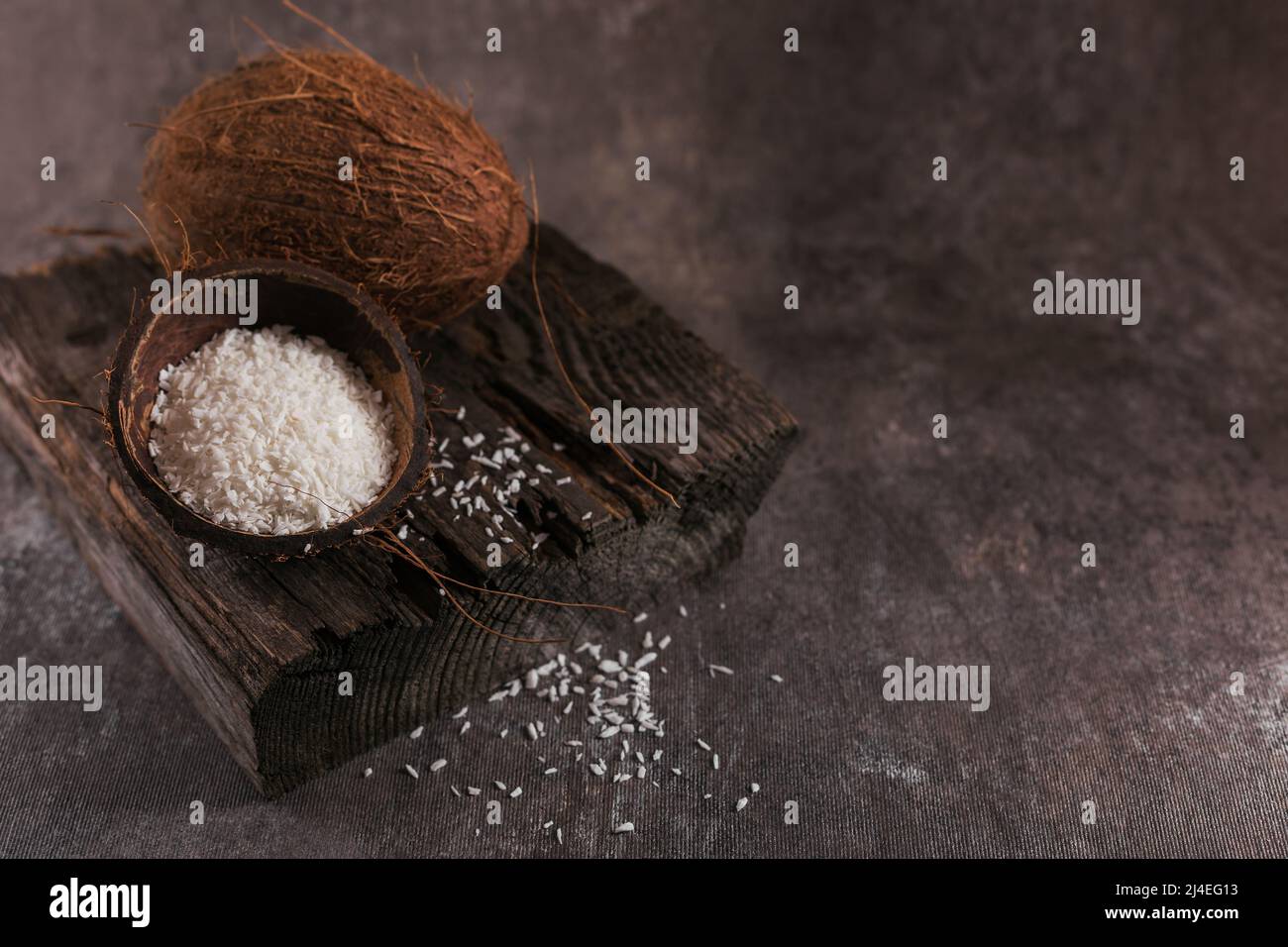 Whole coconut with coconuts flakes on a dark background Stock Photo - Alamy