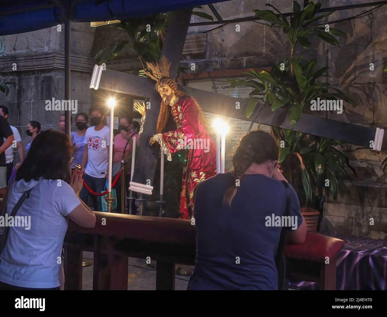 Manila, Philippines. 14th Apr, 2022. Catholic devotees kneel while praying outside San Agustin ...