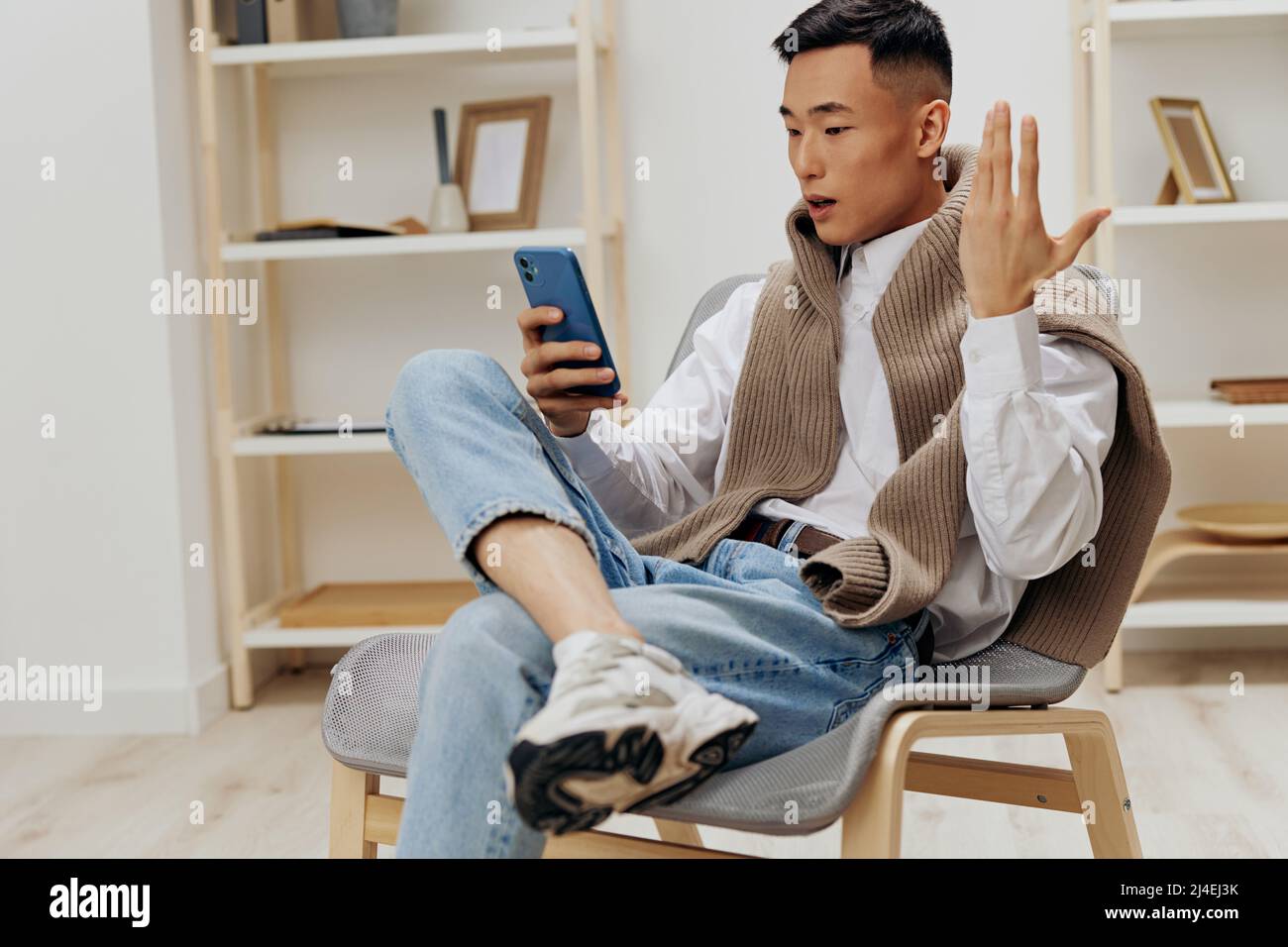 handsome man communication with the phone in his hands sits on a chair ...