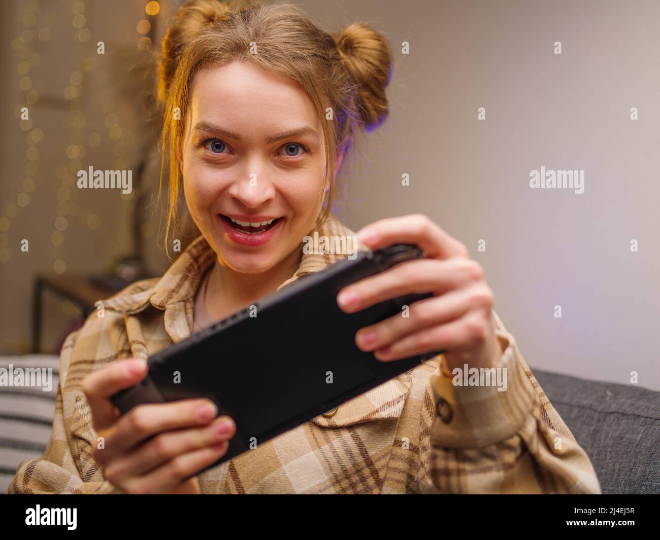 Cheerful girl plays a video game on a portable game console. Close-up ...