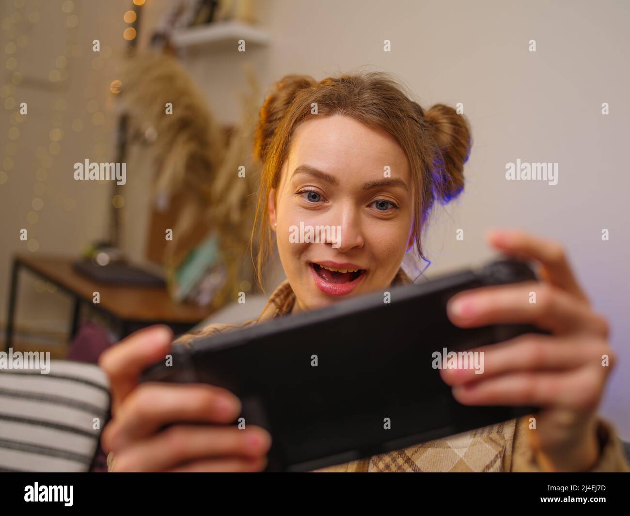 Girl student looks in surprise at the screen of a portable game console ...