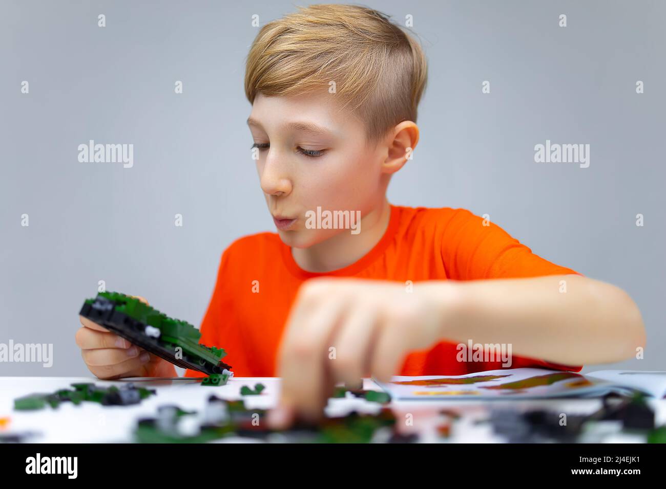 a boy plays with a plastic constructor chooses details for the ...