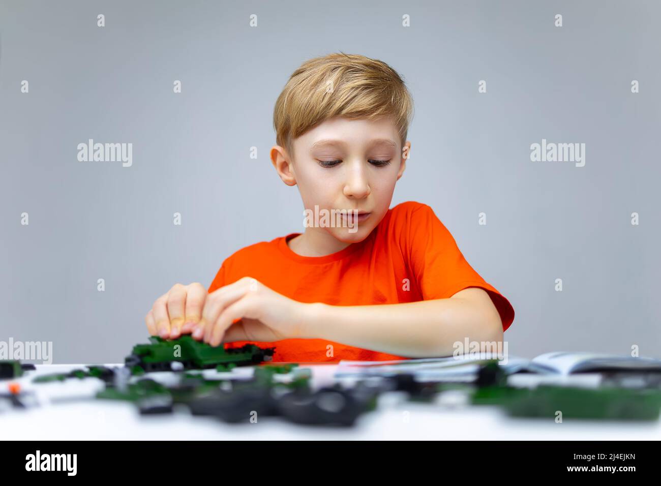 the boy is playing with a plastic constructor, he will make ...
