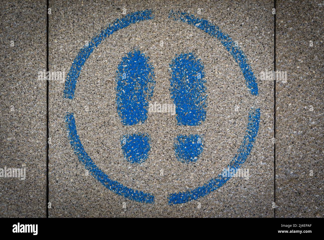 Pavement spray painted sign showing two blue feet marks inside a circle ...