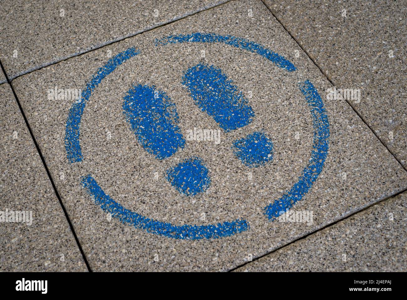 Pavement spray painted sign showing two blue feet marks inside a circle ...