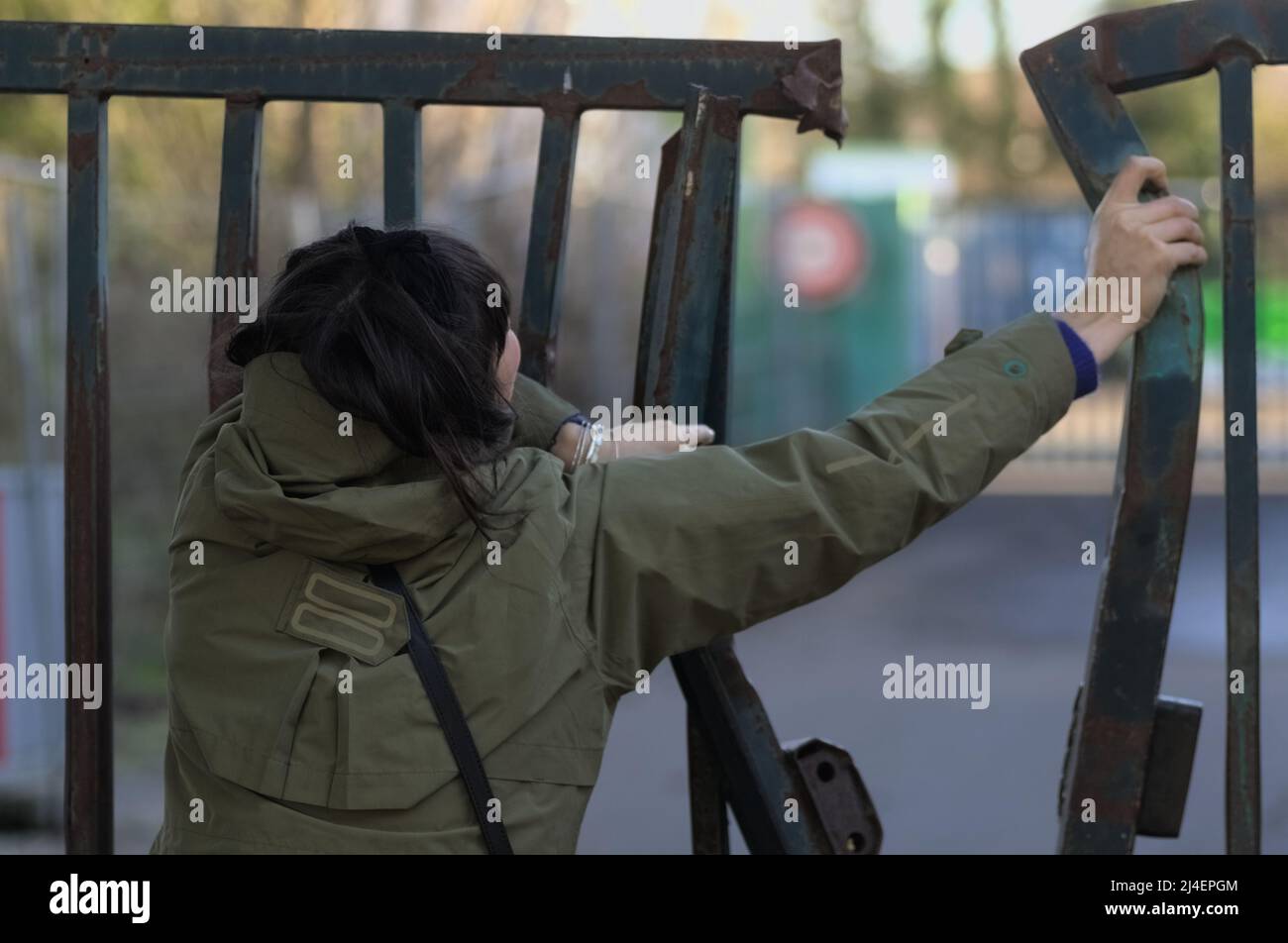 Woman appears to force a gate open Stock Photo - Alamy
