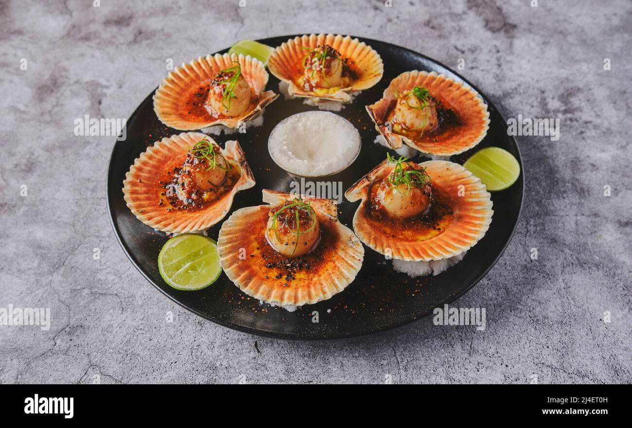 Scallops with flamed shells on a black plate. Luxury restaurant food ...