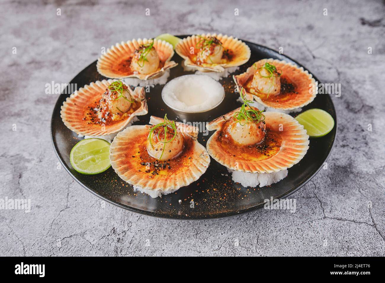 Scallops with flamed shells on a black plate. Luxury restaurant food ...