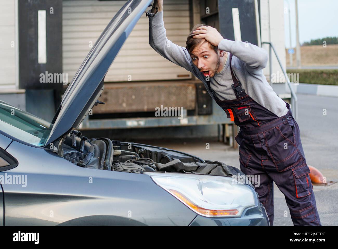 Shocked technician mechanic looks inside the car. Engine trouble Stock ...