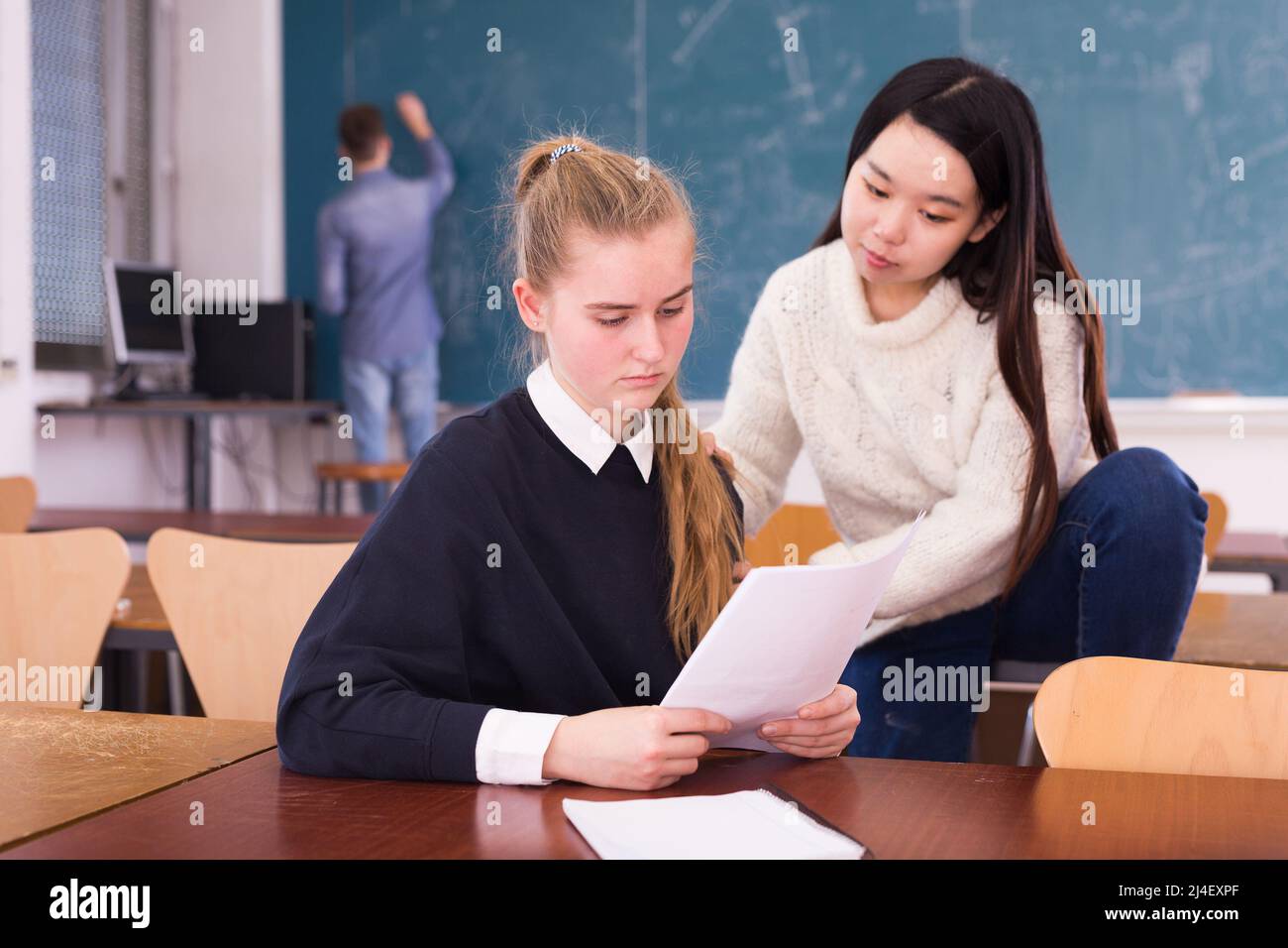 Asian girl classmate comforting upset student girl Stock Photo - Alamy