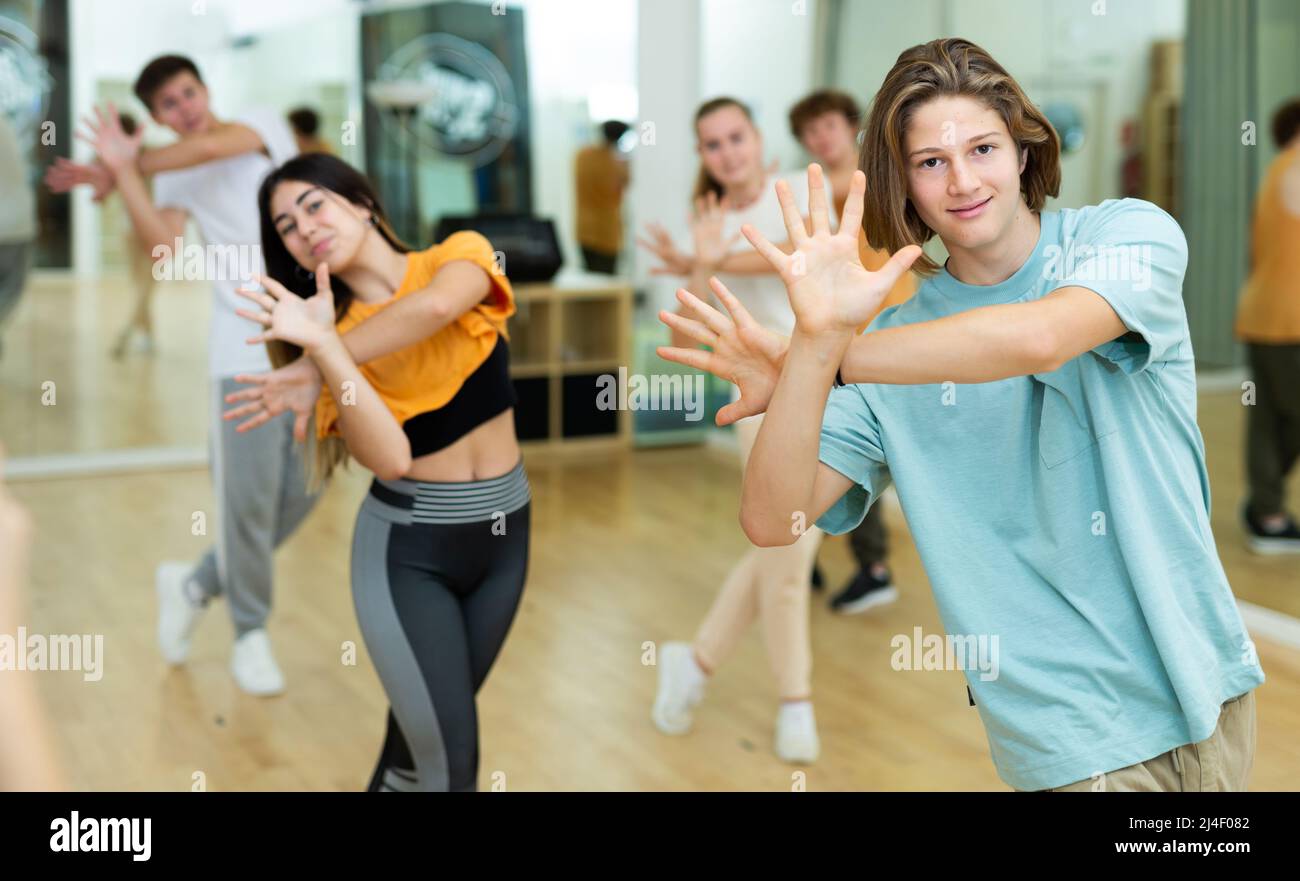 Smiling teenage boy practicing active dance with group in studio Stock ...