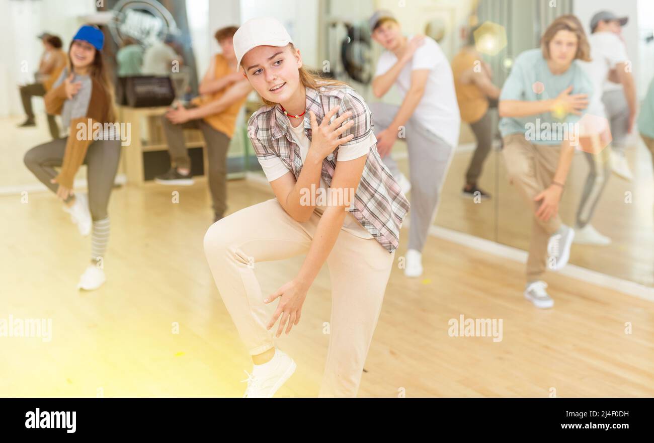 Teenage girl practicing hip-hop movements during group dance lesson ...