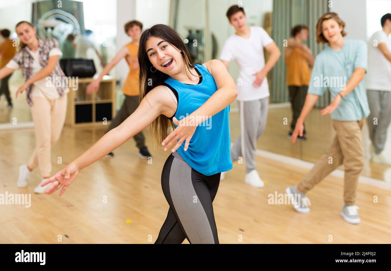 Cheerful emotional teen girl training dance movements in choreography ...