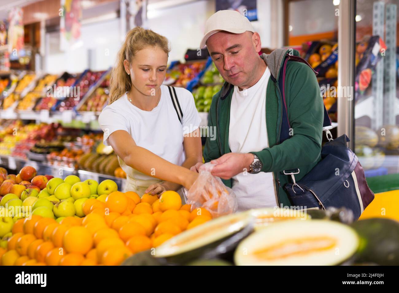 Man with a fifteen-year-old girl choose oranges at the counter Stock ...