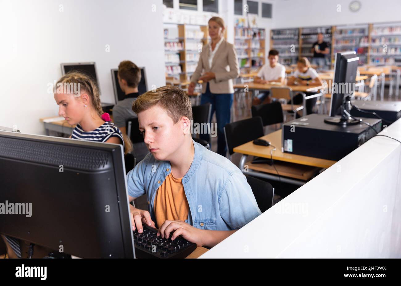 Pupils using computers at lesson, teacher teaching them Stock Photo - Alamy