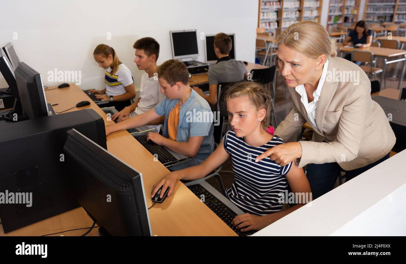 Schoolgirl using computer and teacher teaching she Stock Photo - Alamy