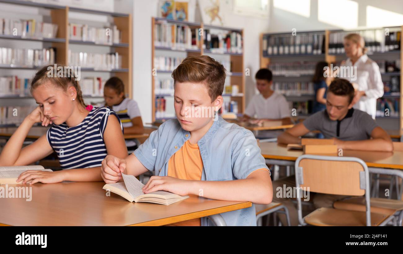 Boy preparing for lesson in school library, reading textbooks Stock ...