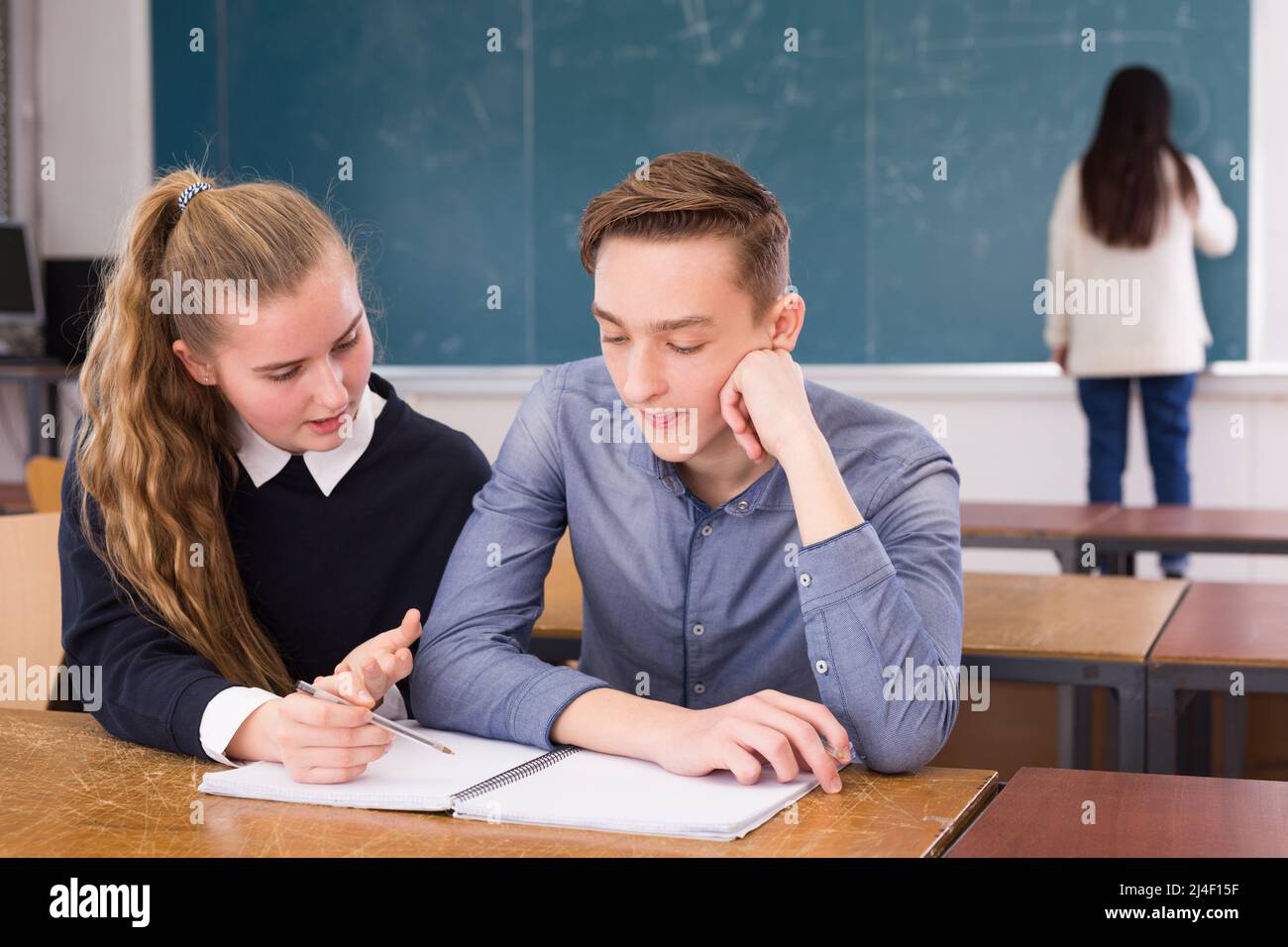 Young guy and girl students doing lesson in classroom Stock Photo - Alamy
