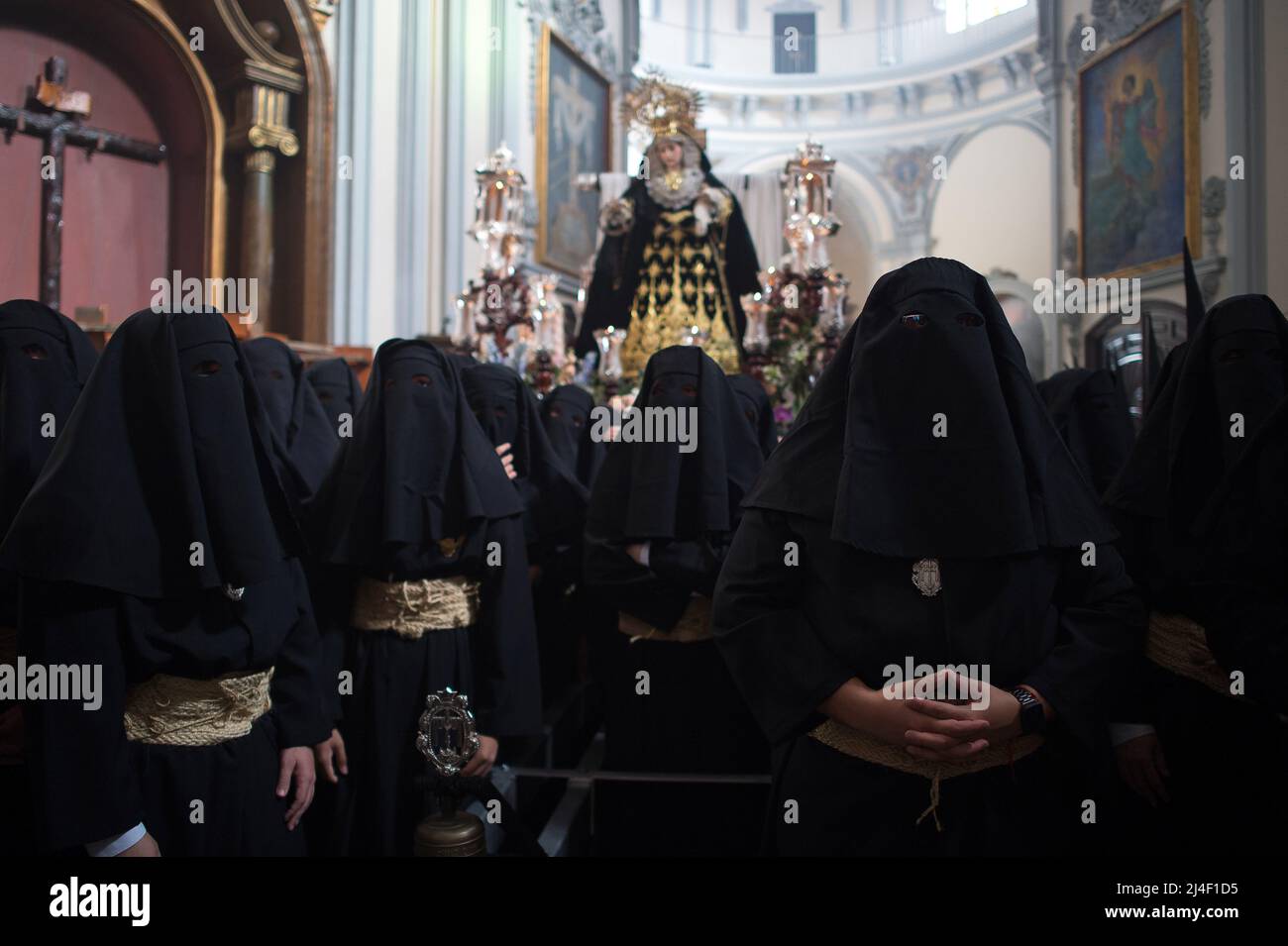 Penitents of “Santa Cruz” brotherhood covered with black hoods are seen ...