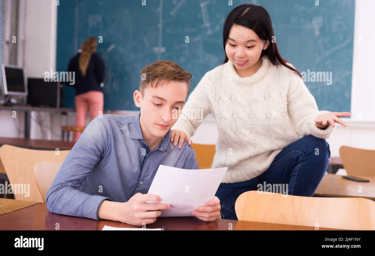 Teen student with asian girl classmate checking test results Stock ...