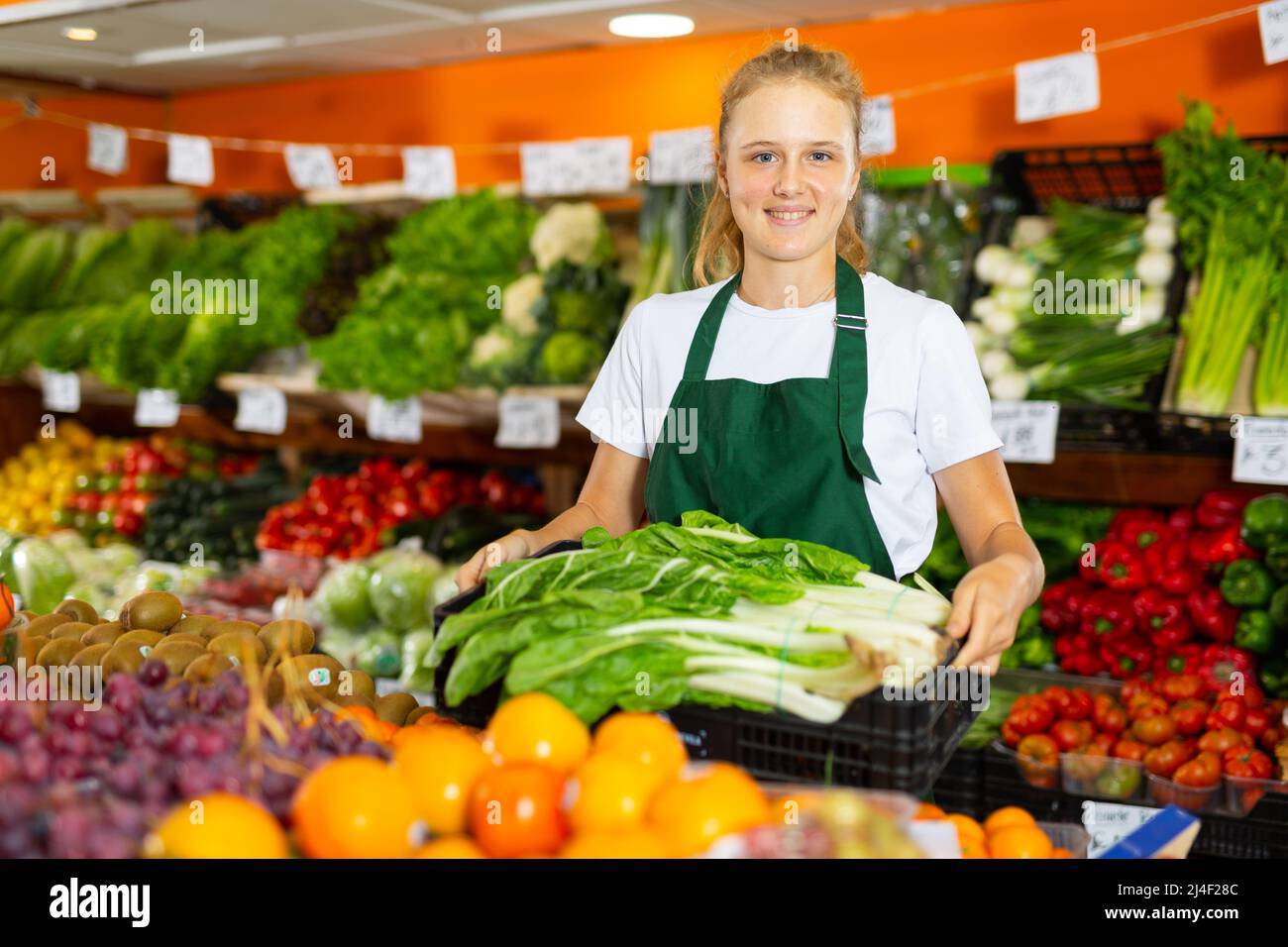 Teenage girl in uniform posing with salad in grocery shop Stock Photo ...
