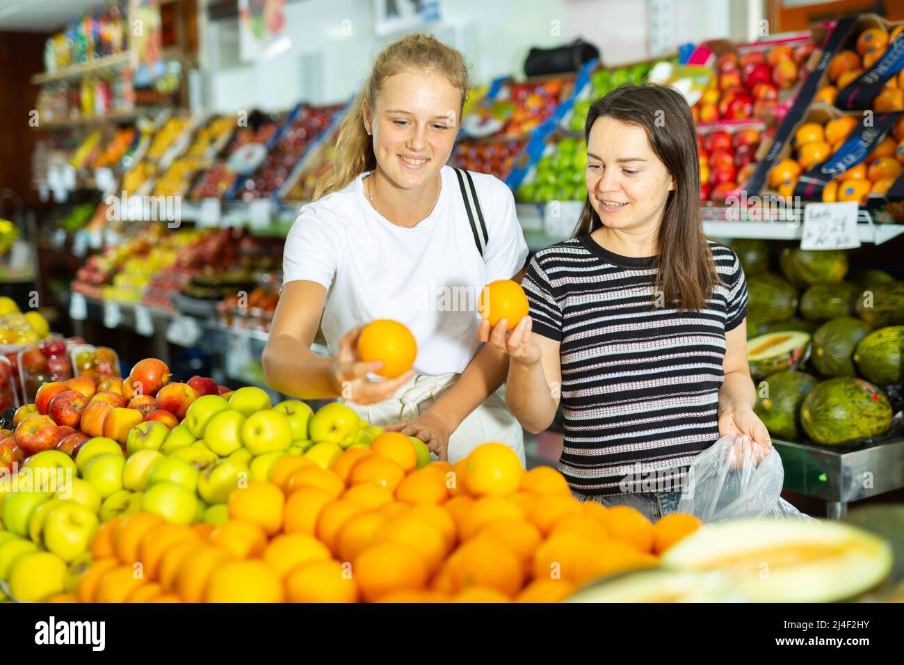Two women choosing oranges at grocery Stock Photo - Alamy