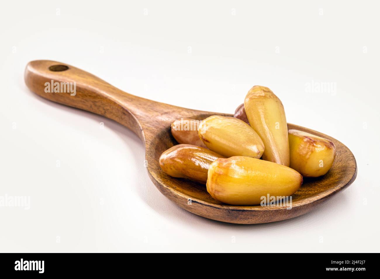 cooked pine nut seed in rustic wooden spoon, copyspace, isolated white ...