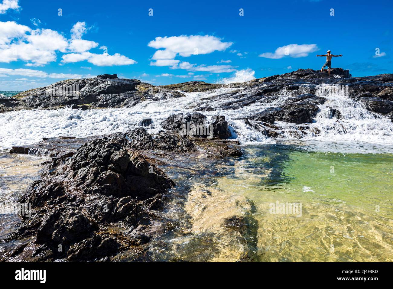 A male tourist enjoying the sun and water at Champagne Pools on Fraser ...
