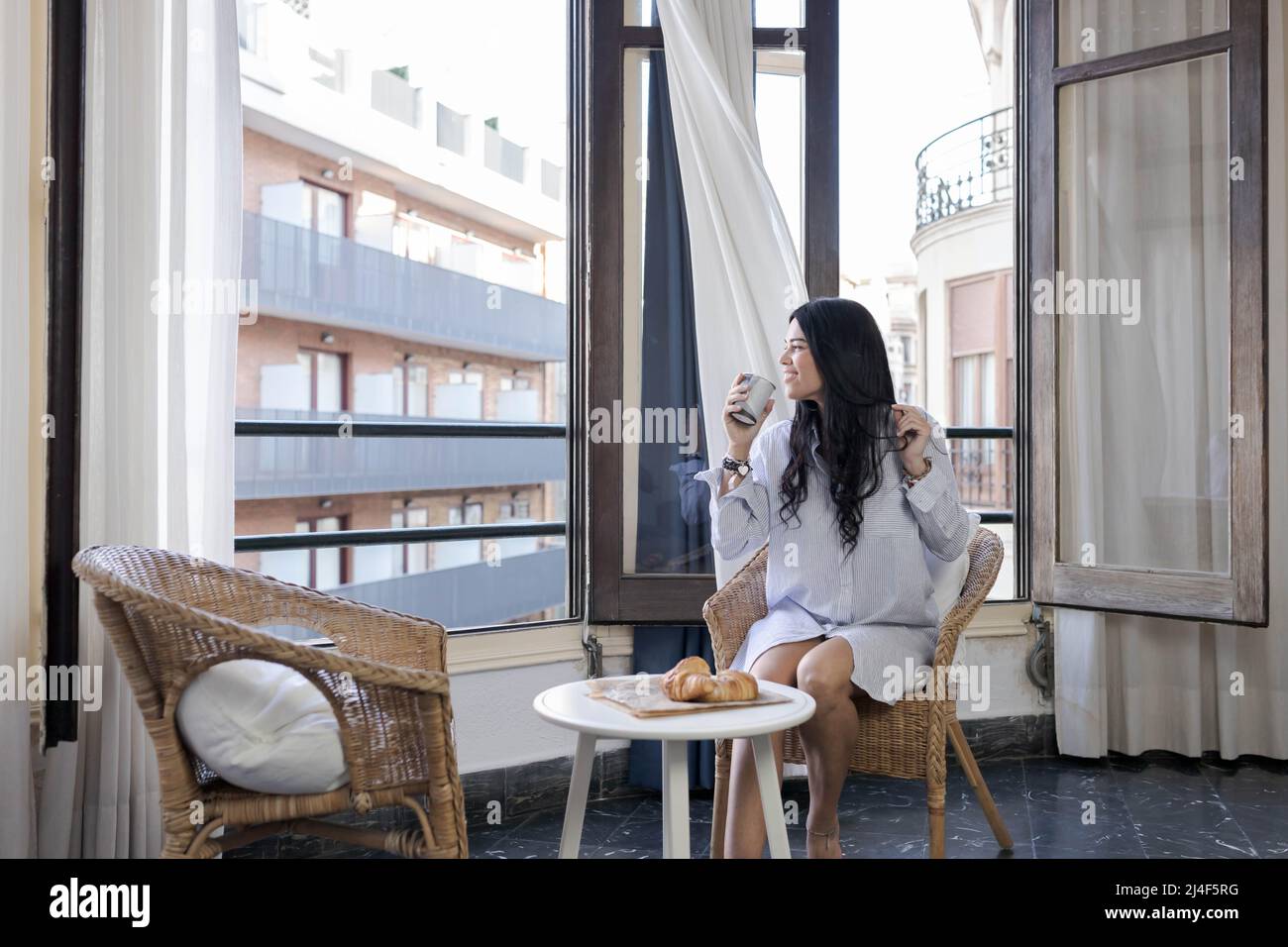 Happy rich young woman wear night robe stand at big window open lace ...