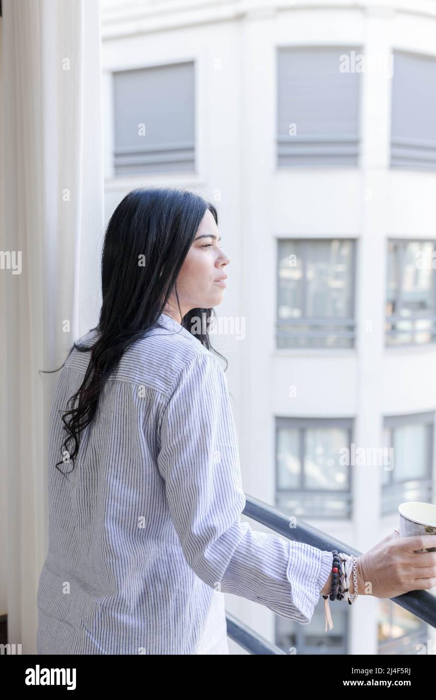 Happy rich young woman wear night robe stand at big window open lace ...