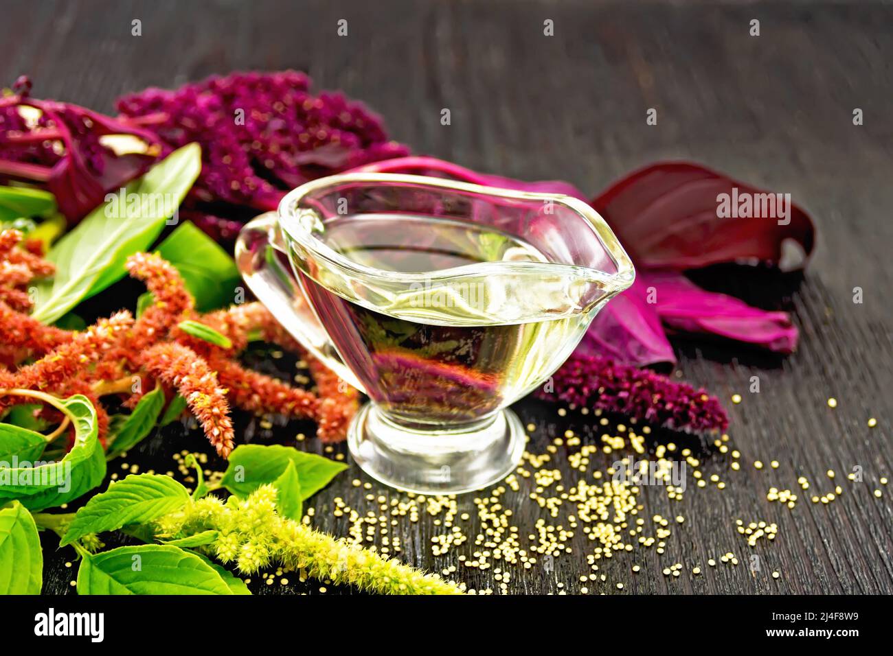 Amaranth oil in a glass gravy boat, brown, green and purple flowers and ...
