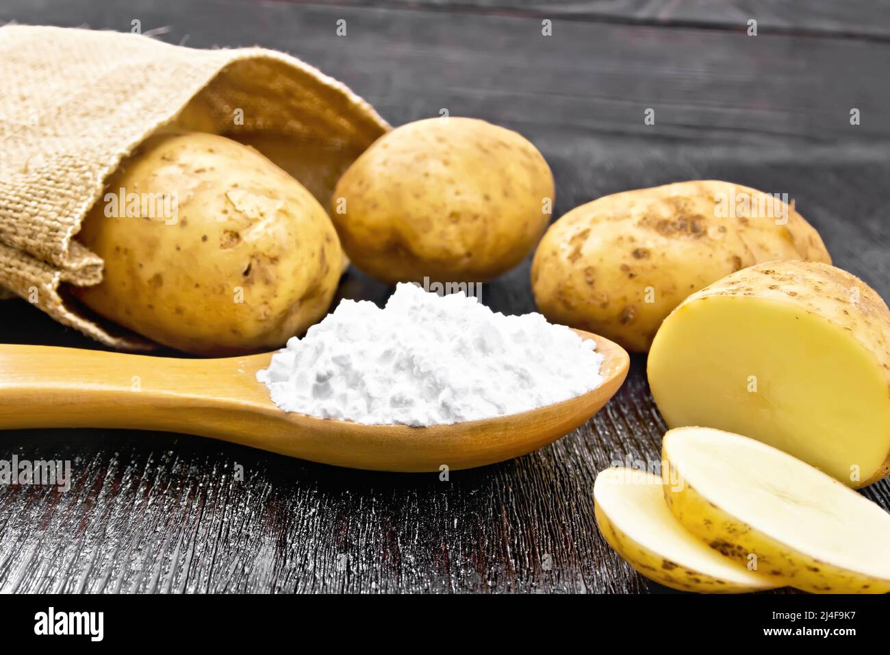 Potato starch in a spoon, vegetable tubers in a bag and on table ...