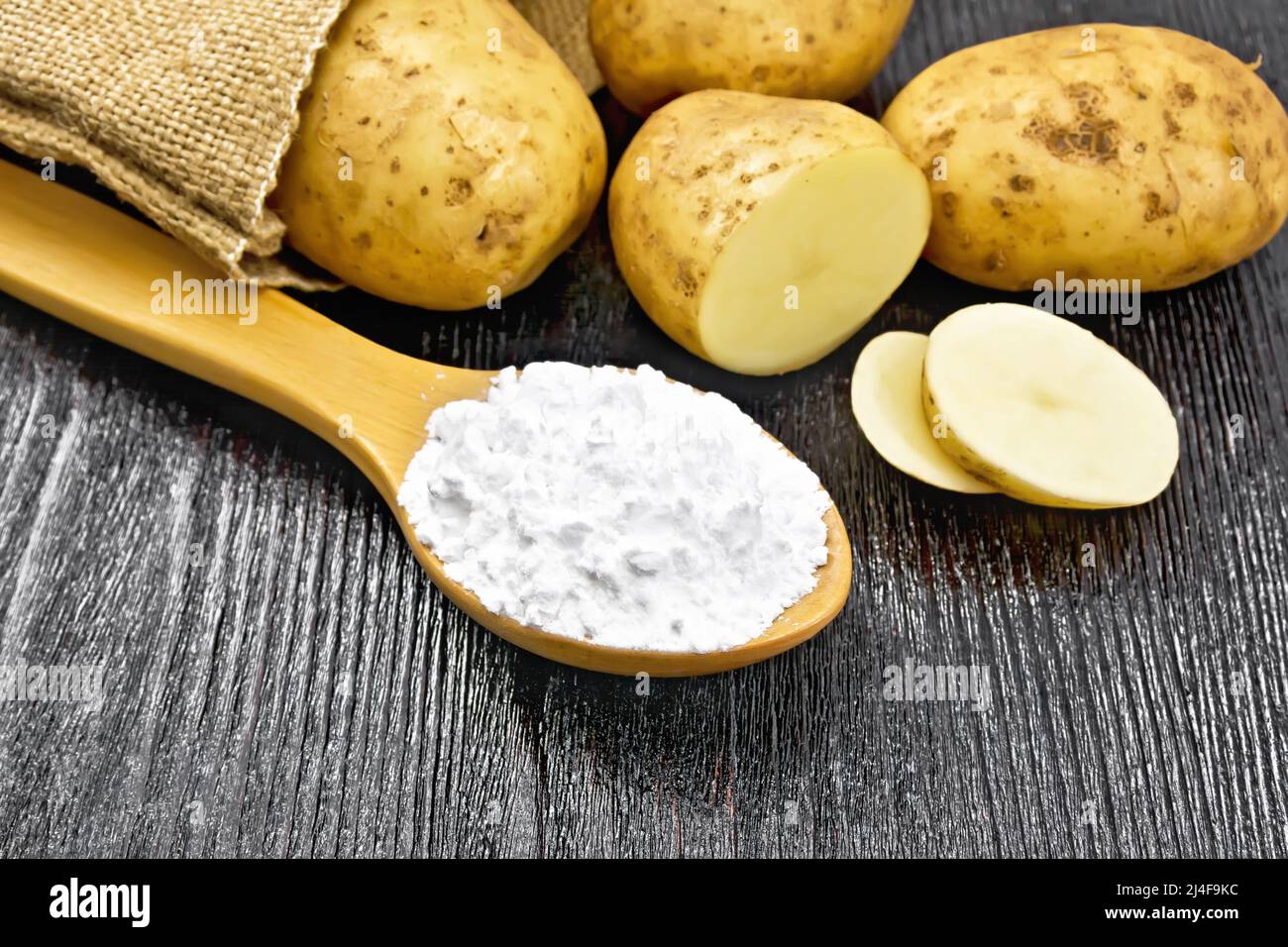 Potato starch in a spoon, vegetable tubers in a bag and on table ...