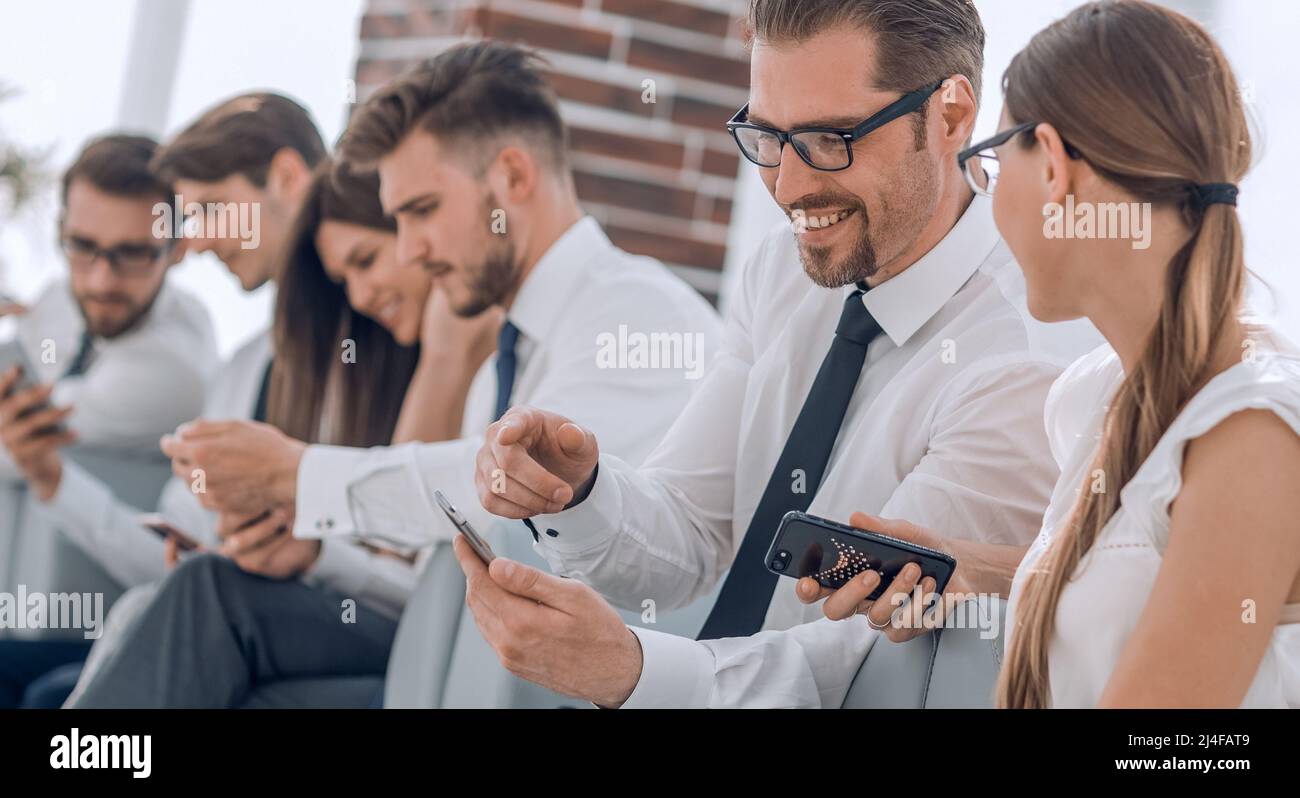 employees of the company using their smartphones sitting in the office ...