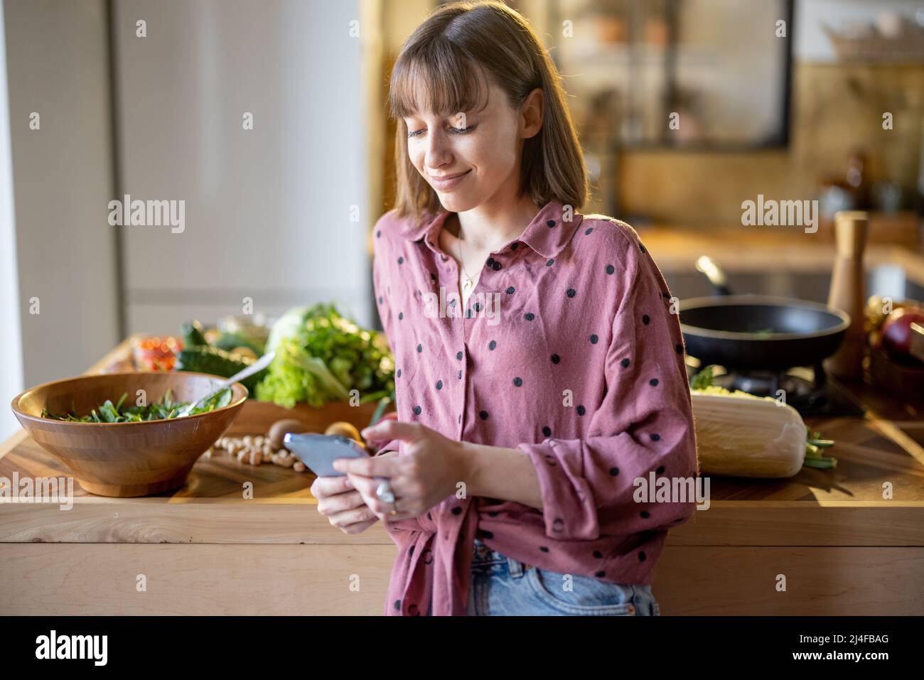 Woman using smatphone while cooking healthy at home Stock Photo - Alamy