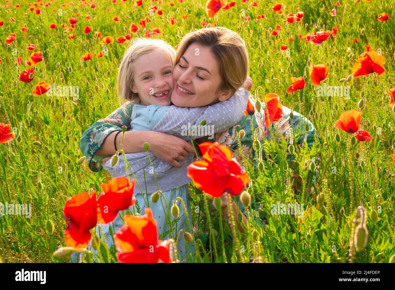 Mother and daughter hugging in a poppies meadow. Mom and child girl ...